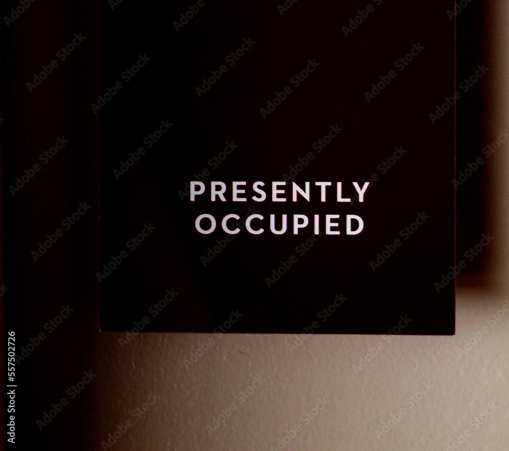Black sign hanging on door that says Presently Occupied Stock Photo ...