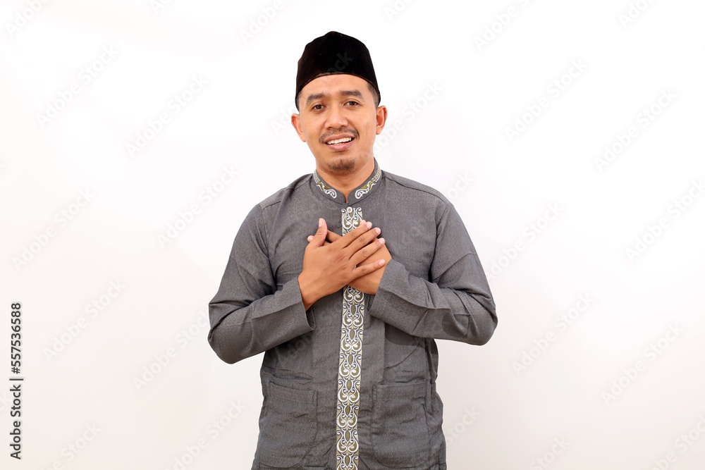 Relieved relaxed asian muslim man standing while holding his chest ...