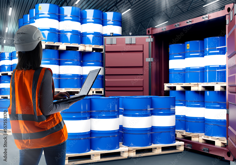 Oil logistics. Woman with laptop in warehouse. Blue barrels near ...