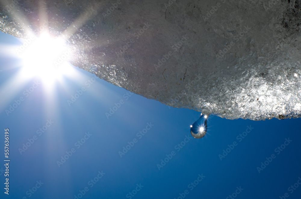 Drop of water flowing from a block of melting ice heated by the sun ...