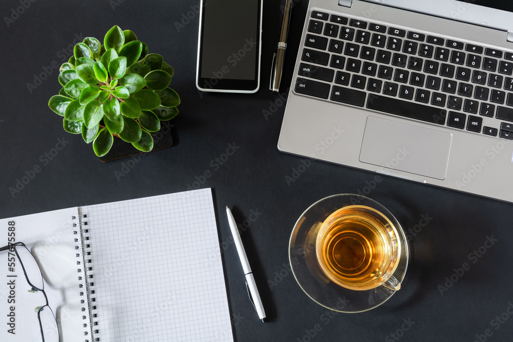 Workplace with laptop, notebook with pen, cup of tea and smartphone on ...