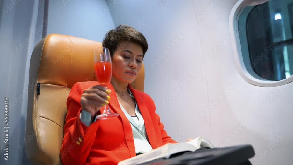 Beautiful business woman reading book while travels on private jet ...