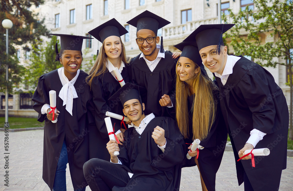 Happy graduates with diplomas posing outside university building. Group ...