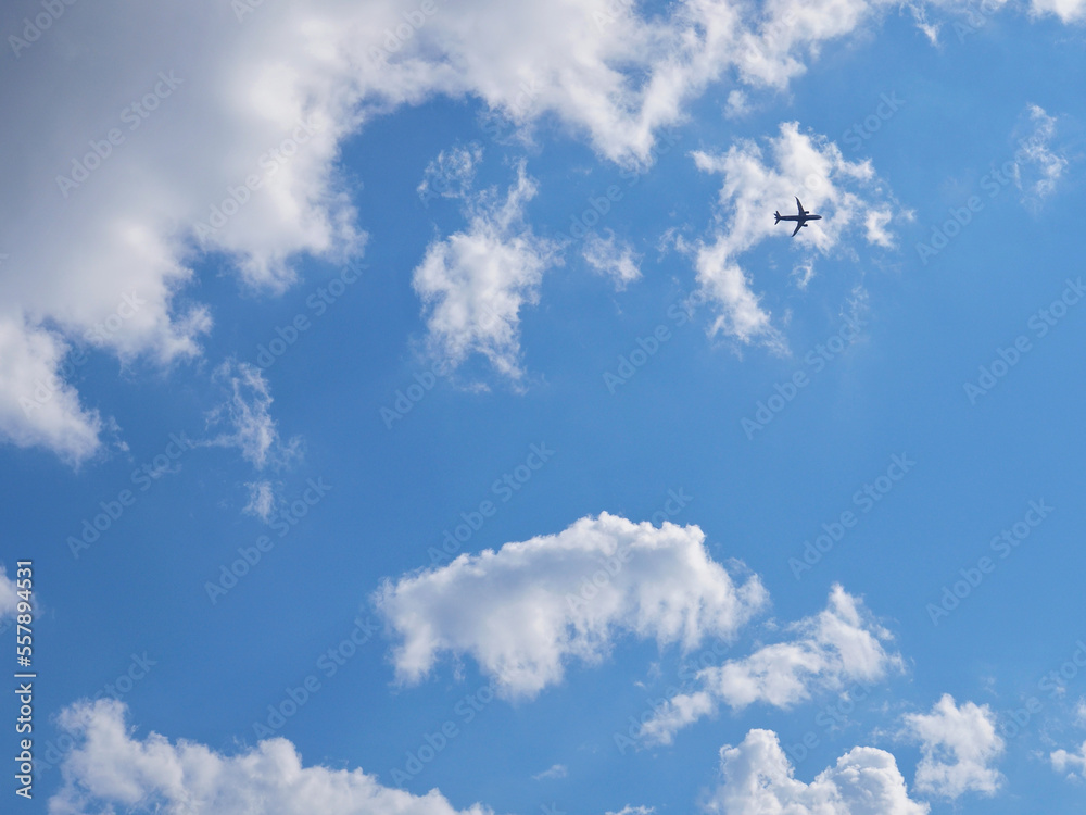 The passenger plane is flying far away in the blue sky and white clouds ...