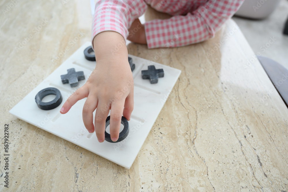 Closeup hand of child little girl playing Tic Tac Toe or OX board game ...