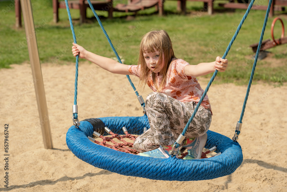 Happy elementary school age girl, child swinging on a modern swing ...