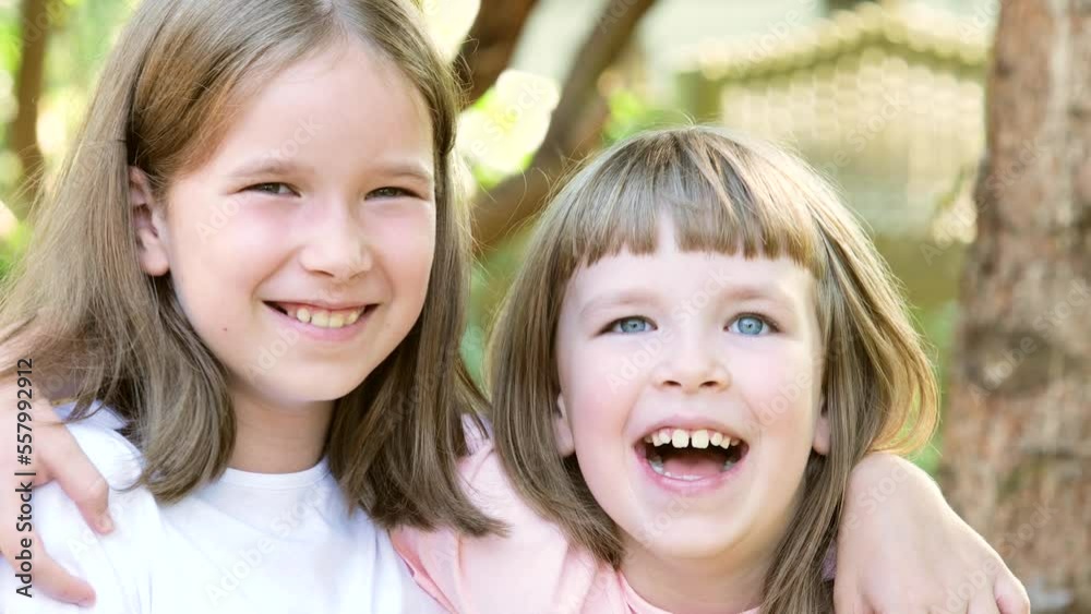 Two young happy cheerful elementary school age girls, children laughing ...