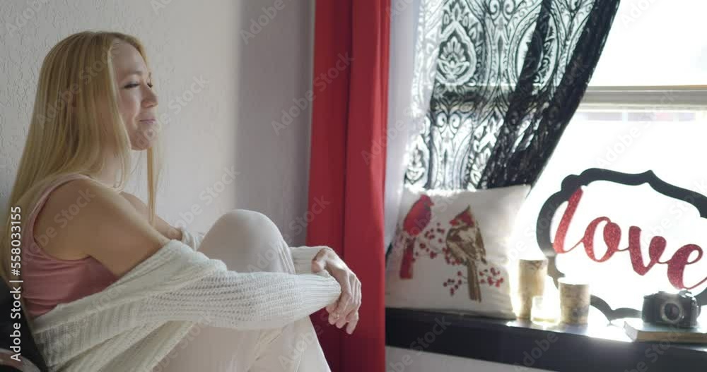 Beautiful blonde caucasian white women sitting next to window with her ...