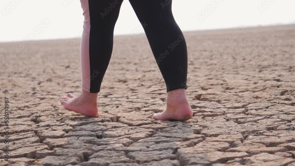 Close up shot of female barefoot walking on drought land of desert at ...