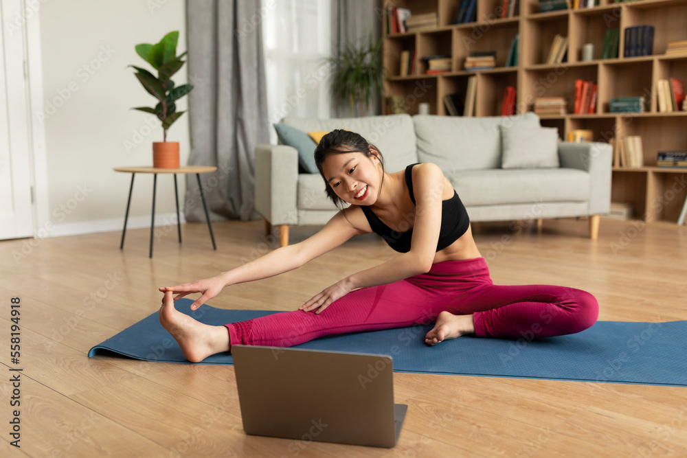 Home training. Young japanese lady stretching leg muscles in front of ...
