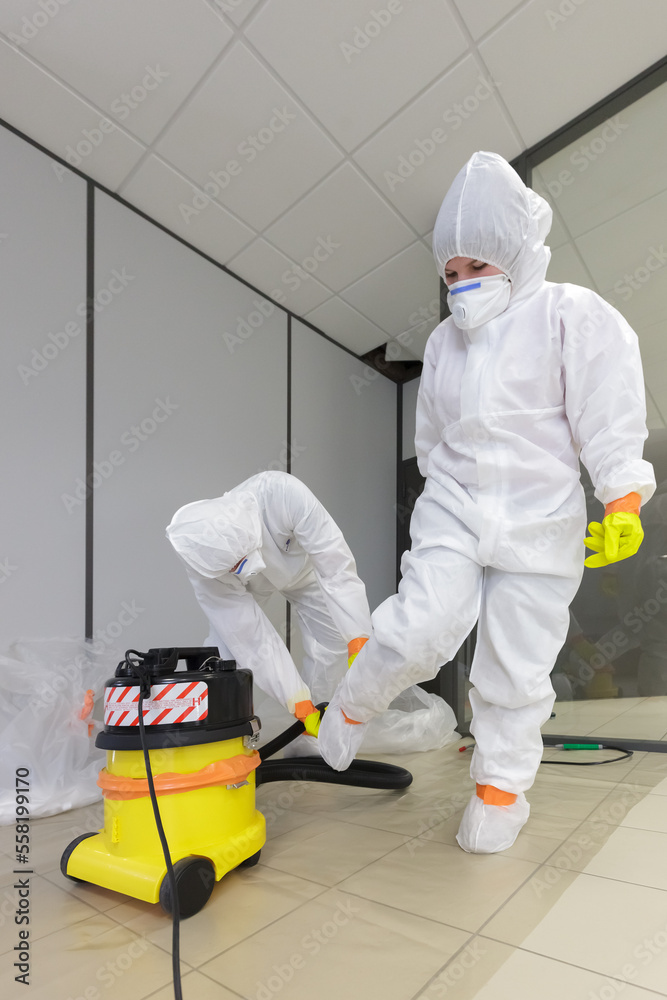 Operators in type 5/6 hazmat suits mutually performing decontamination ...