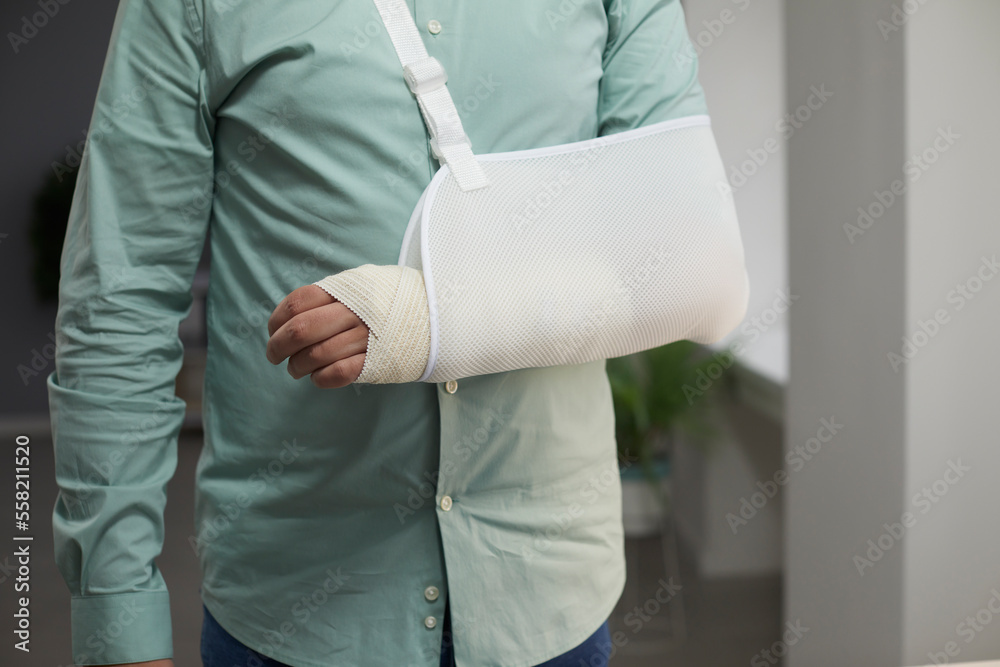 Cropped shot of a man wearing a white bandage and a forearm sling after ...