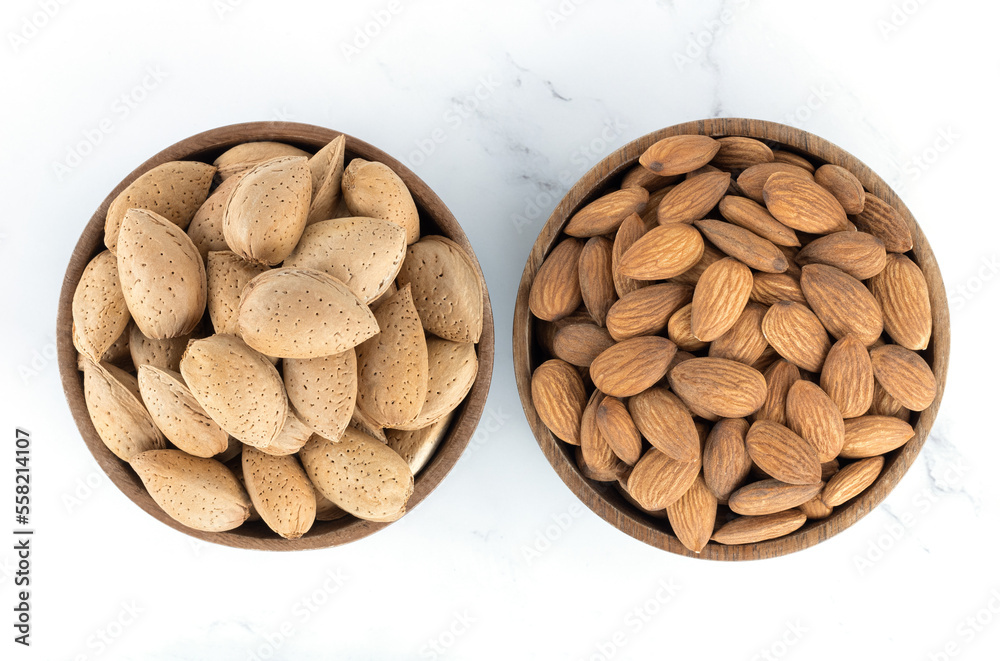 Wooden bowl with shelled almonds and peeled almond kernels on a white ...