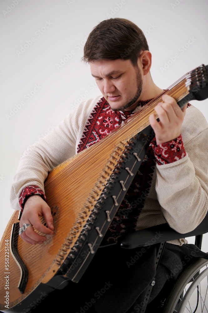 handsome young man with kobza musical instrument in hands sits on white ...