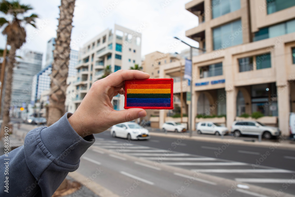 LGBT rainbow gay pride flag in hand on city building background ...