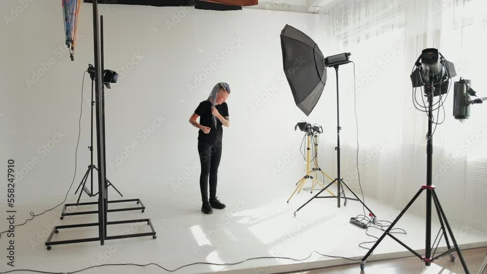 a model girl with dreadlocks and a tattoo is standing in a white studio ...