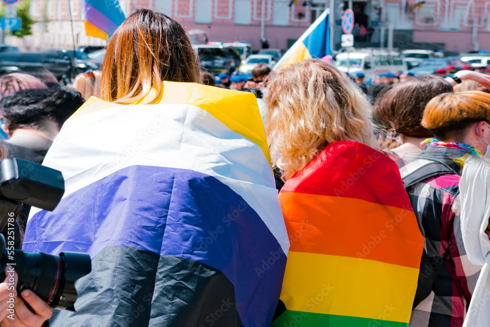 Back view of people with LGBT and non-binary flags protesting on the ...