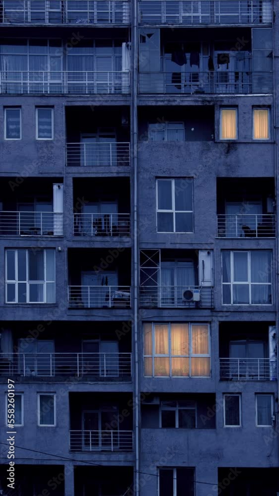 Vertical 4K video. Old Soviet panel house at night. light comes on in ...