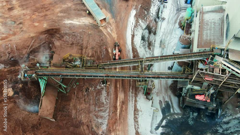 Overhead shot of telescopic wheel loader driving underneath conveyor ...