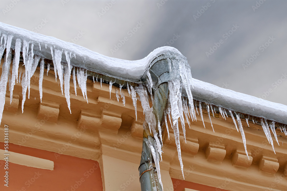 Icy drain pipe with big icicles on roof of residential house. Icicles ...