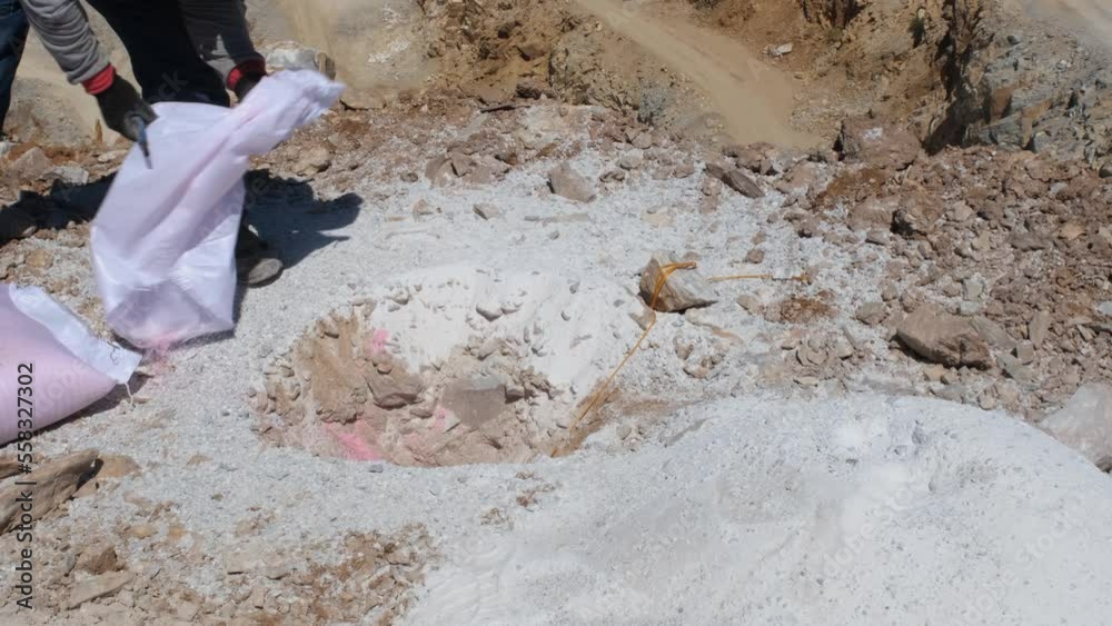 Pouring explosives into dug holes for quarry explosion. Explosive dust ...