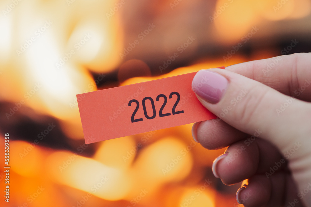 Female hand holding small sheet of paper with "2022" on it, close up ...