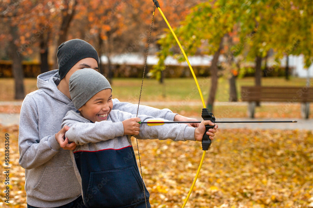 Asian laughing 7 years boy learns to shoot an arrow with the help of ...