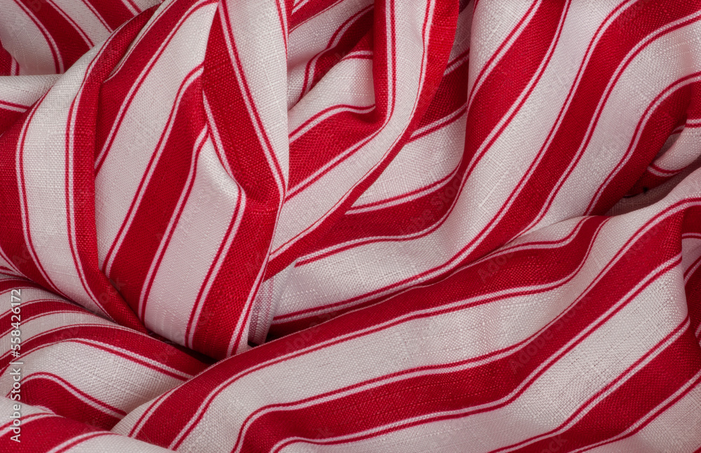 Red and white striped fabric closeup shows folds and swirls of material ...