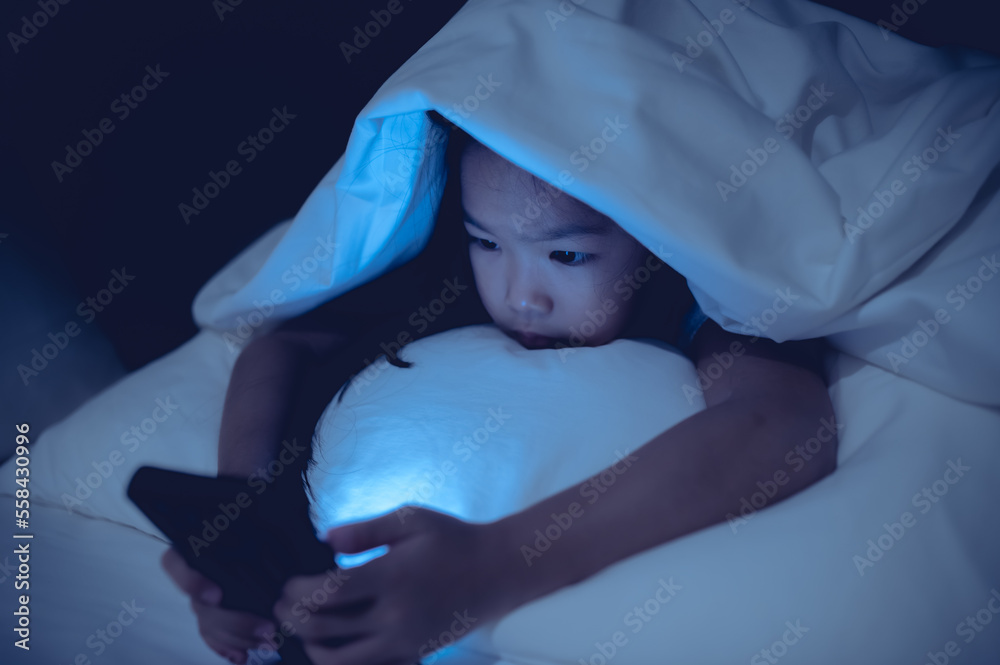 Asian kid playing game on smartphone in the bed at night,The girl ...