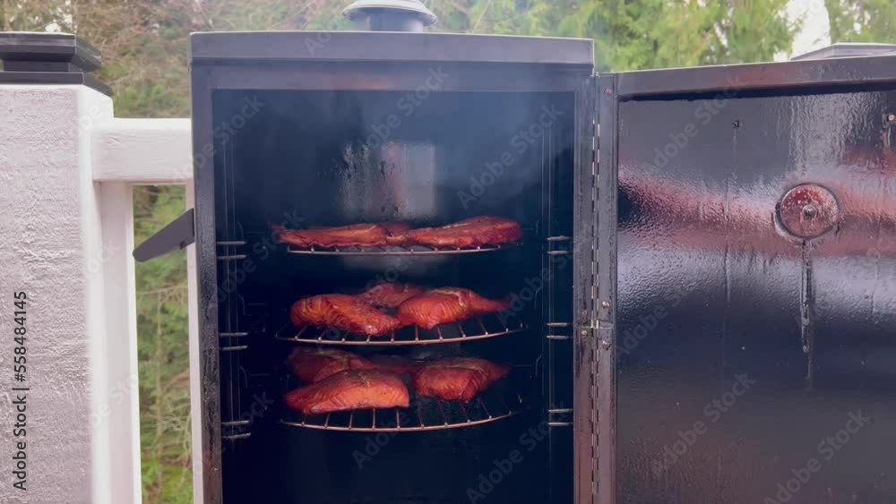 Open smoker with finished smoked salmon trout fillet on racks ready to ...
