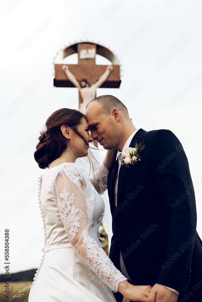 bride and groom holding hands in front of jesus christ statue during ...
