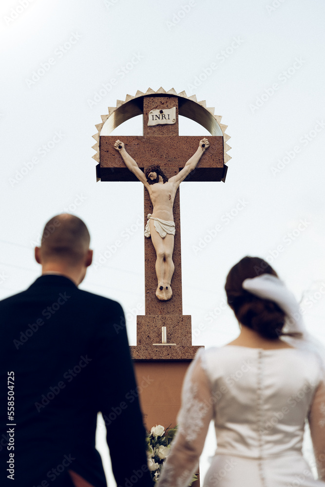 Foto de bride and groom holding hands in front of jesus christ statue ...