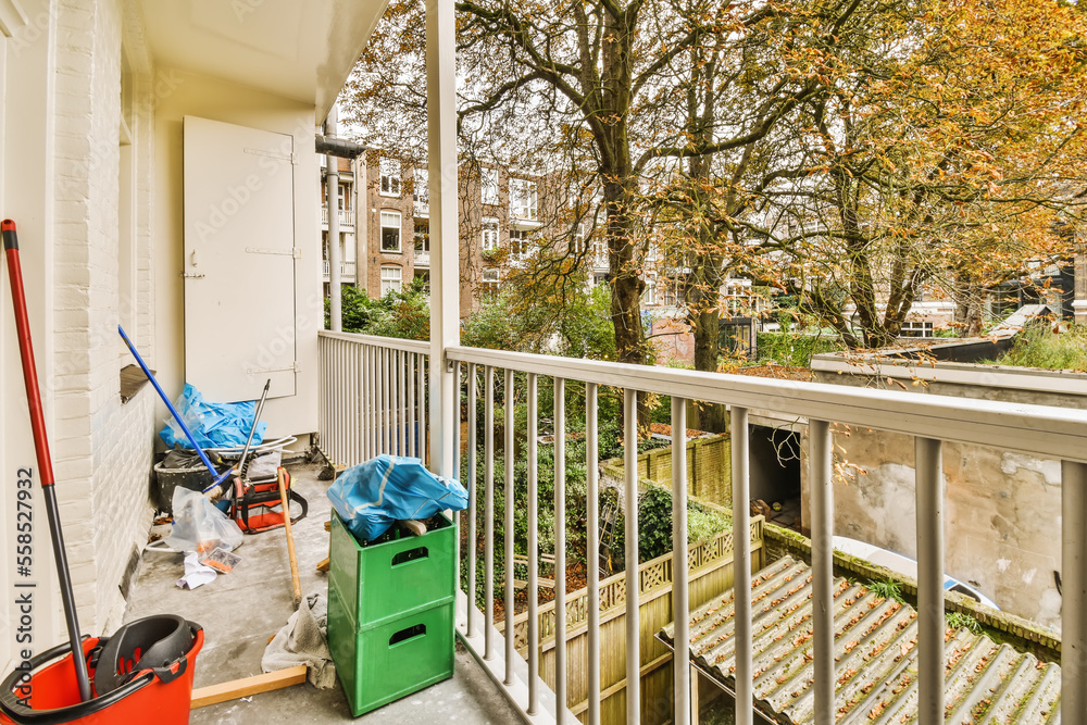 a balcony with trash bins and mops on the floor next to an open door ...
