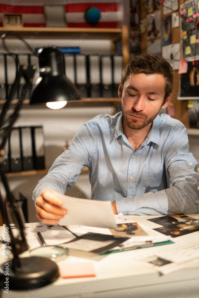 Detective looking the photos of criminals who recorded a hidden camera ...