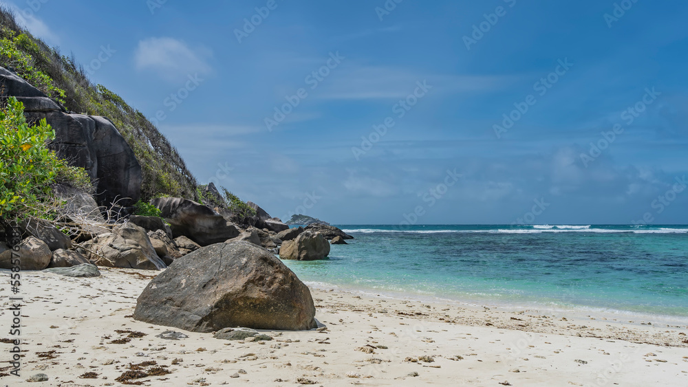 Secluded tropical beach. Boulders on the sand and at the water's edge ...