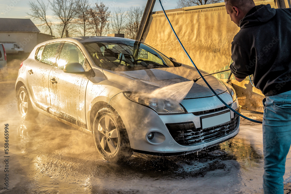 Male driver washing his car with contactless high pressure water jet in ...