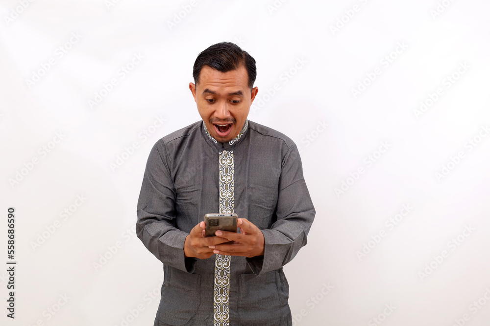 Wow expression of Asian man standing while holding a cell phone ...