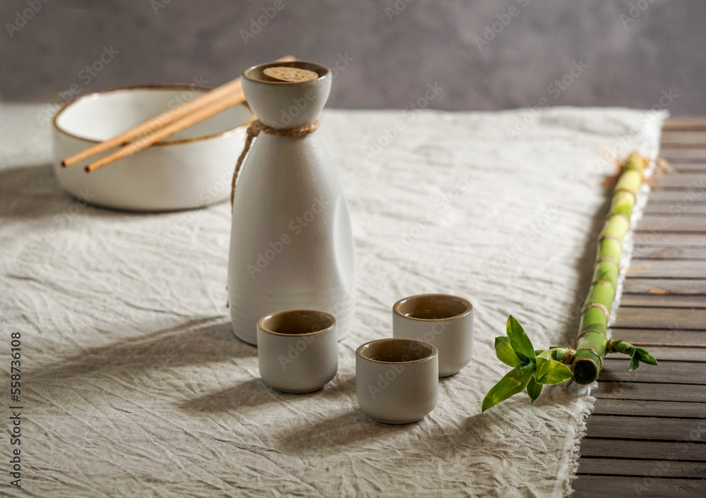 Japanese sake still life with a sprig of bamboo, light linen background ...