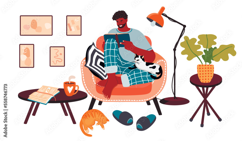 Young man reading a book at cozy home. Male is sitting in a comfortable ...