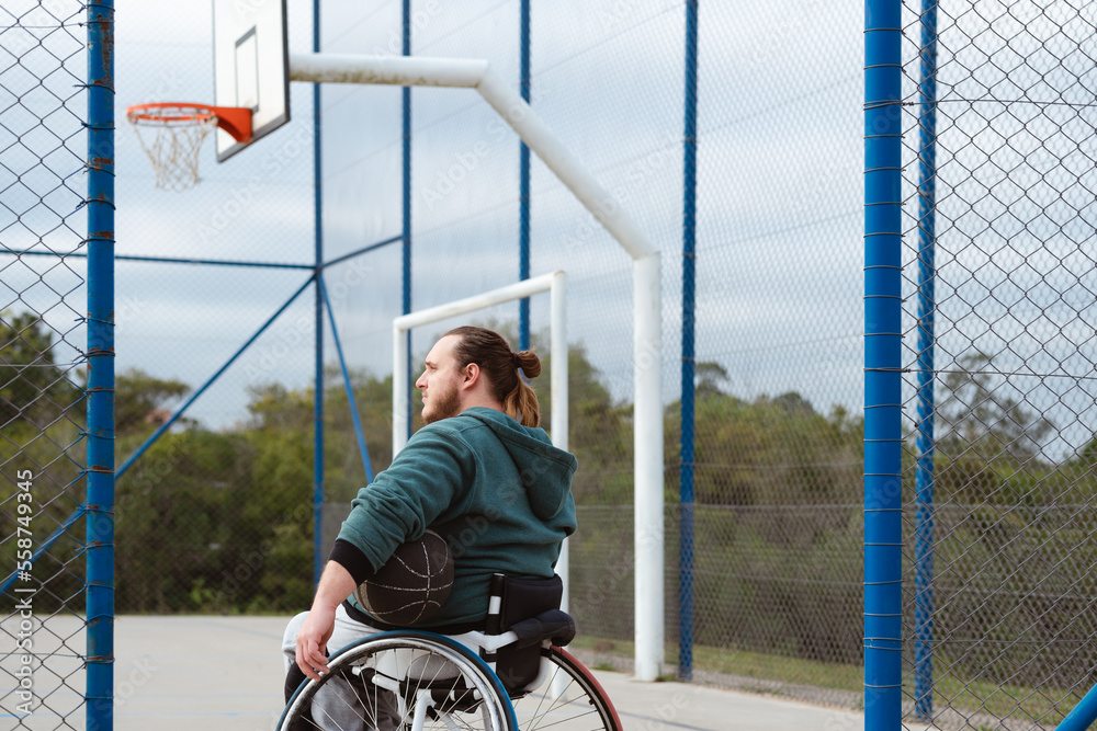 disabled man in wheelchair holding ball under arm in open basketball ...