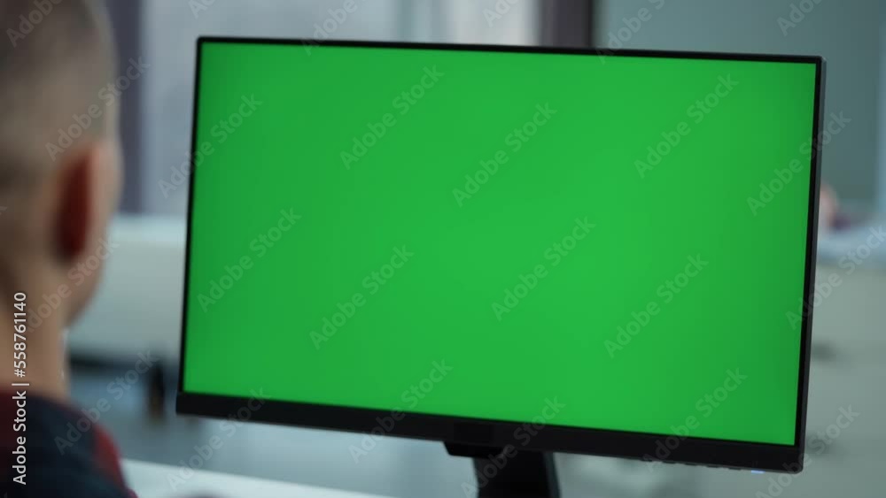 Young Man Working At Computer With Green Mock Up Screen Sitting At Desk ...