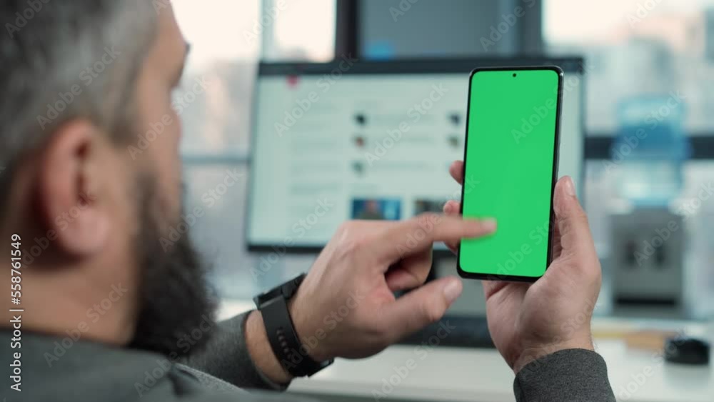 Man Sitting In Office Uses Smartphone With Green Screen Mock Up Display. Man Makes Gestures ...