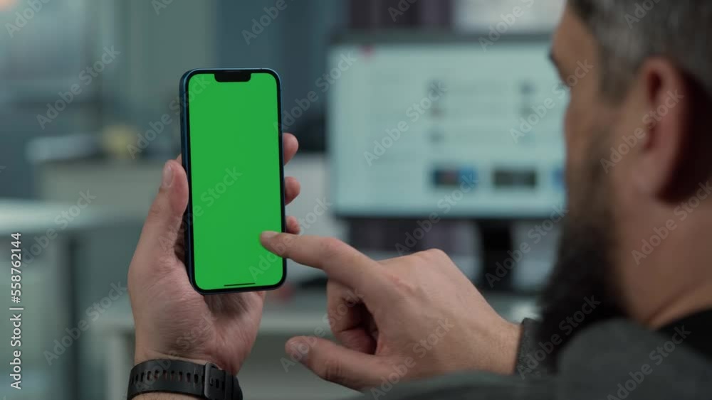 Man Sitting In Office Uses Smartphone With Green Screen Mock Up Display. Man Makes Gestures ...