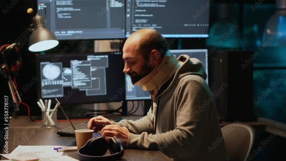 Adult Programmer With Neck Collar Foam Coding Html Script Using Laptop And Multiple Monitors At