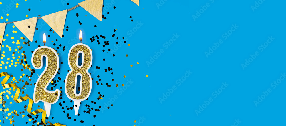 Number 28 gold celebration candle on star and glitter blue background ...