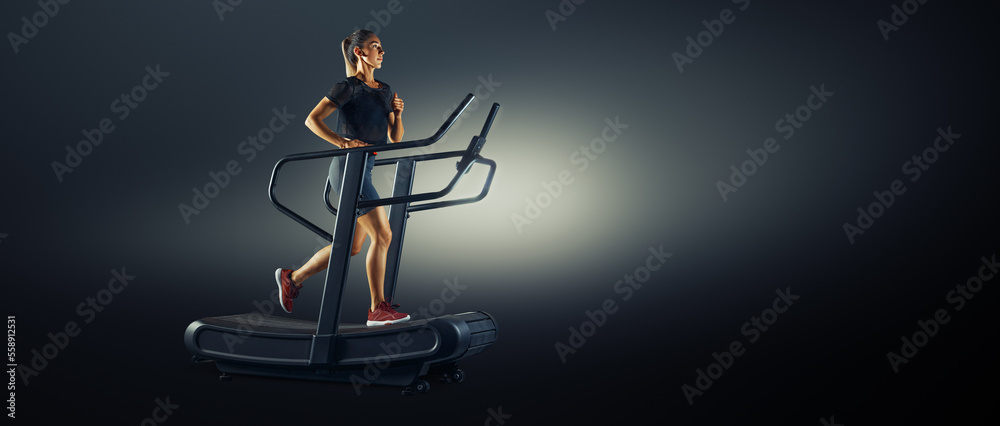 Full length profile shot of a young sporty female athlete running on a ...