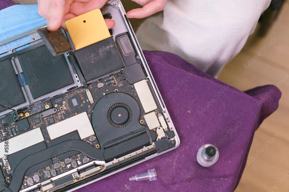 Man removing the battery of a laptop from adhesive stripes via a ...