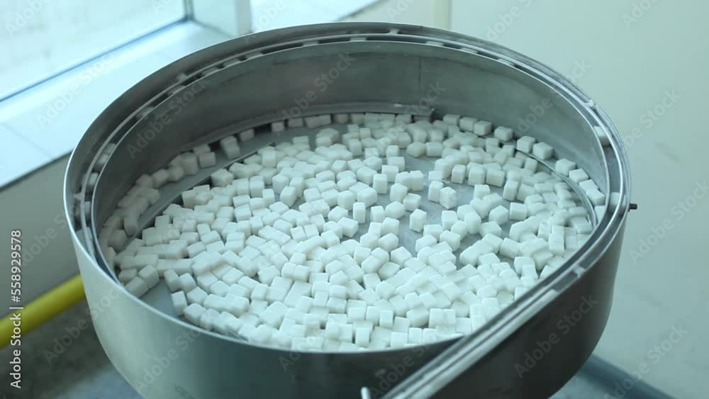Refined sugar moves along a conveyor belt to be packed in paper ...