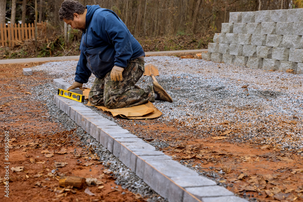 Construction worker is installing arranging precast concrete pavers ...
