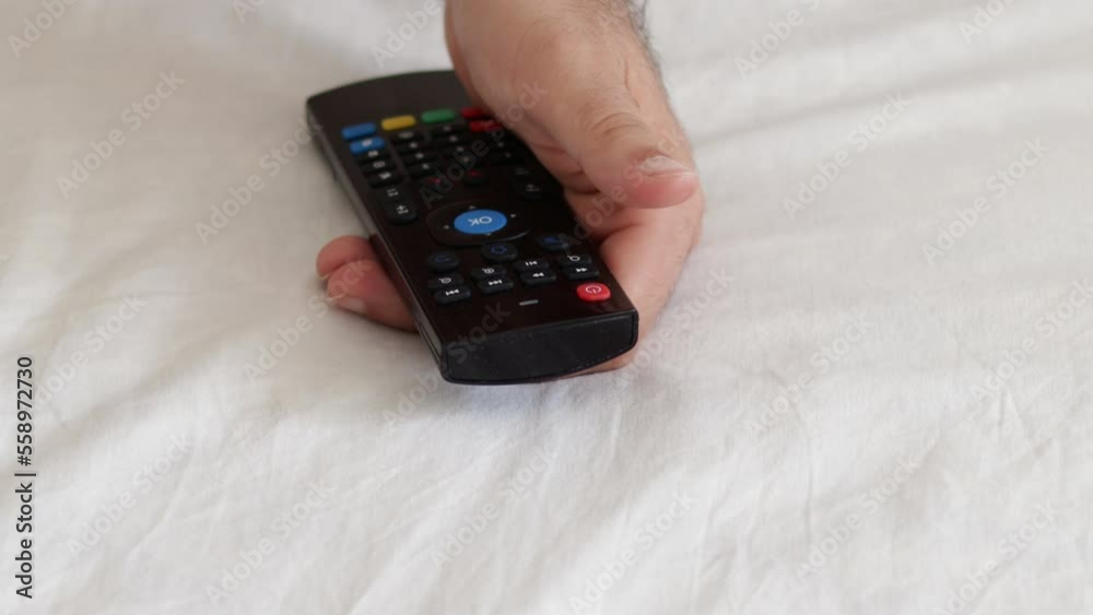 cute baby boy playing with remote tv control sitting on bed naket ...